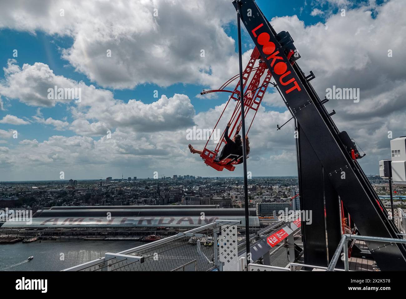 A daring person swings from a tall crane over Amsterdam's cityscape ...