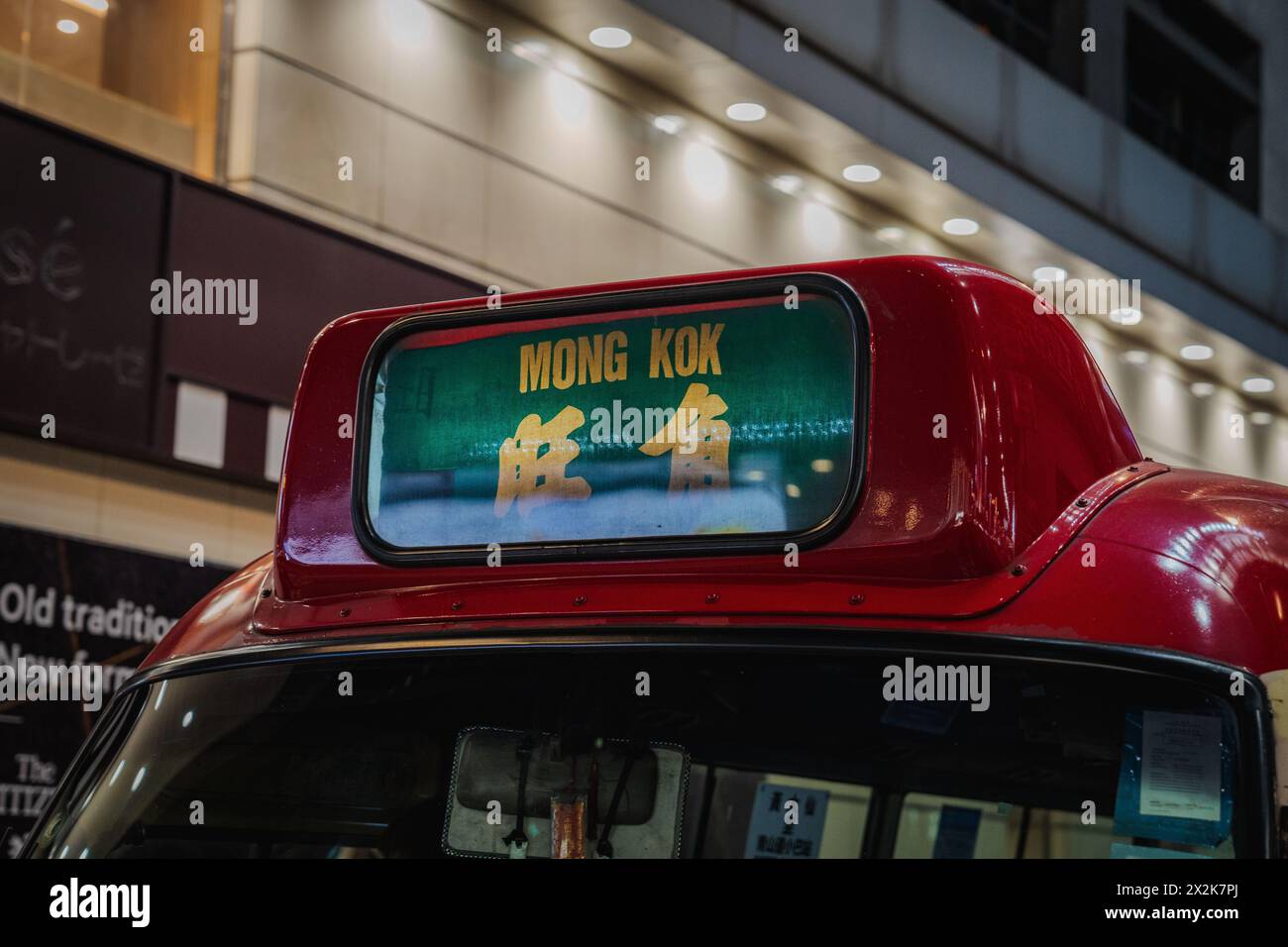 Close-up of a red bus sign lit up at night displaying the name Mong Kok ...