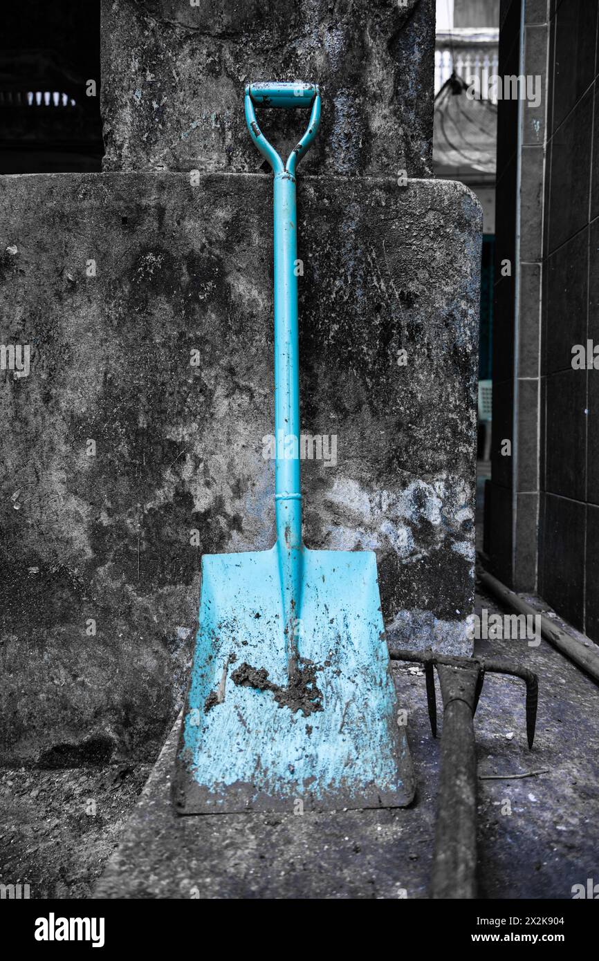 A light blue spade left leaning against a concrete wall in a Bangkok ...