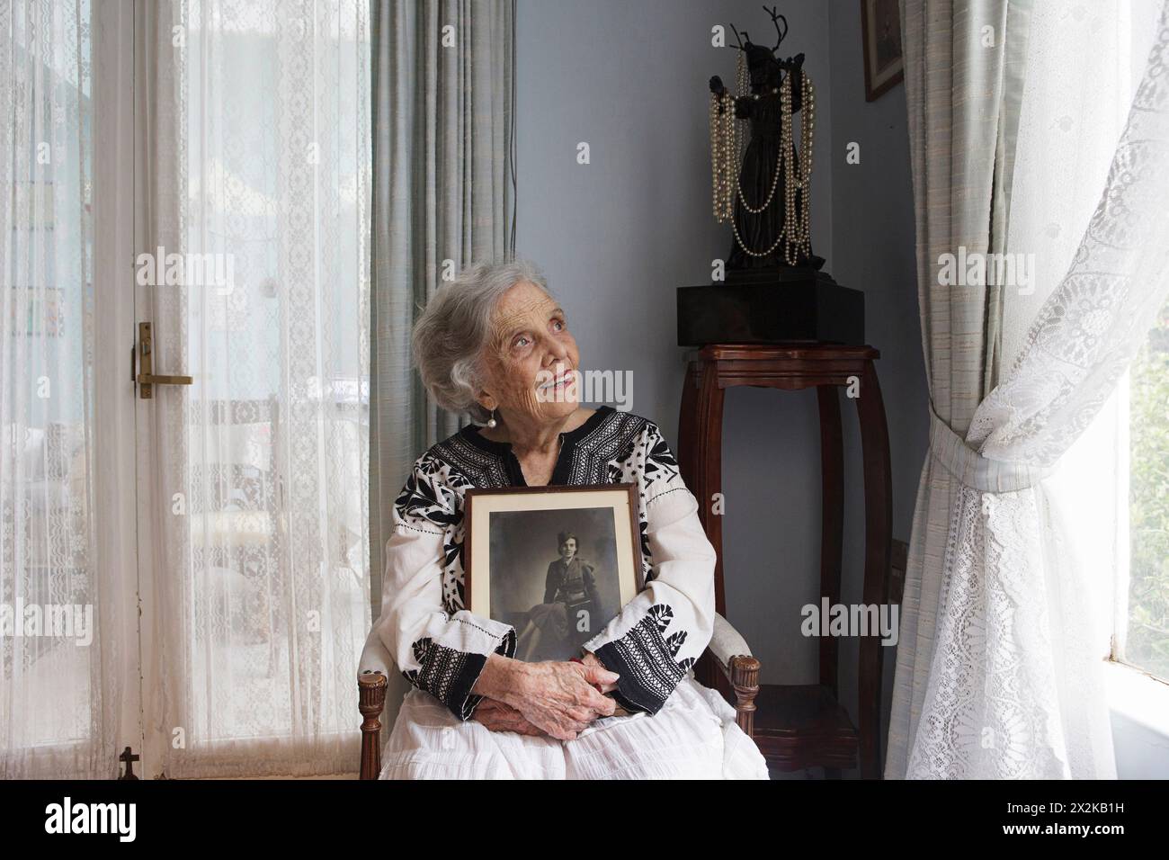 Portrait of Elena Poniatowska at her place holding a photo of her mother photographed during ...