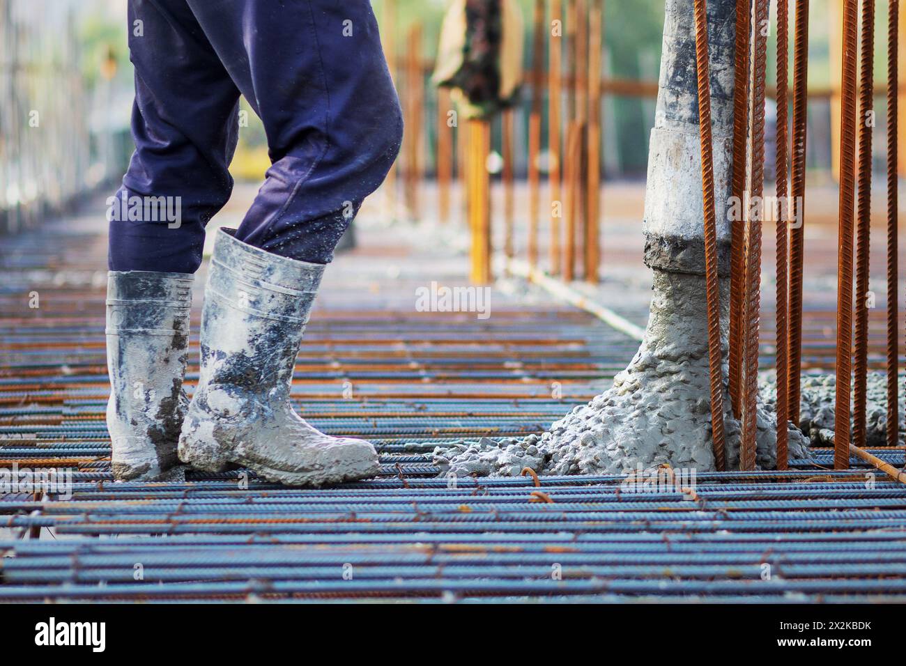 Concrete is poured into a steel reinforcement frame at a construction ...