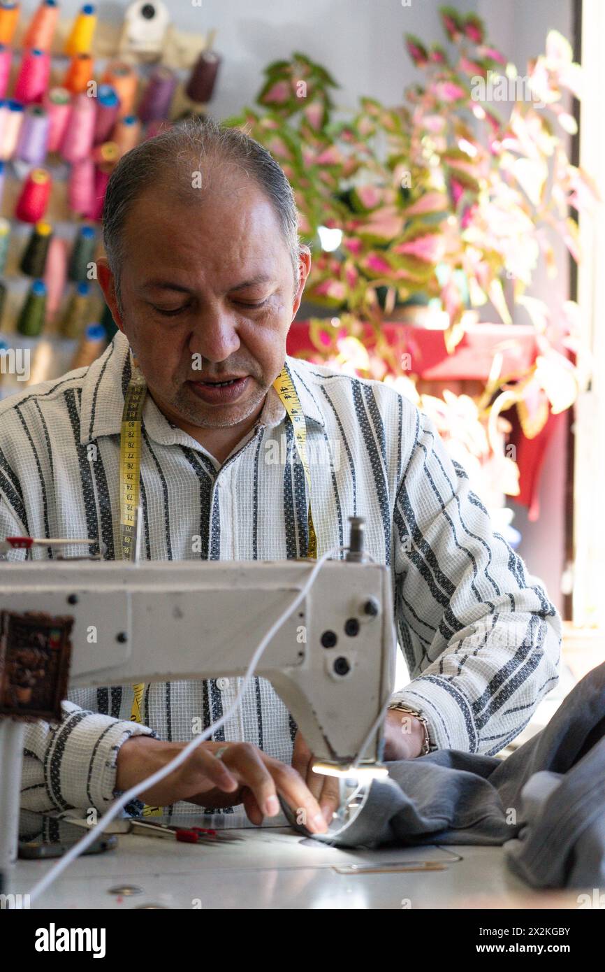 Latin man sewing a piece of clothing in his sewing workshop. 50 year ...