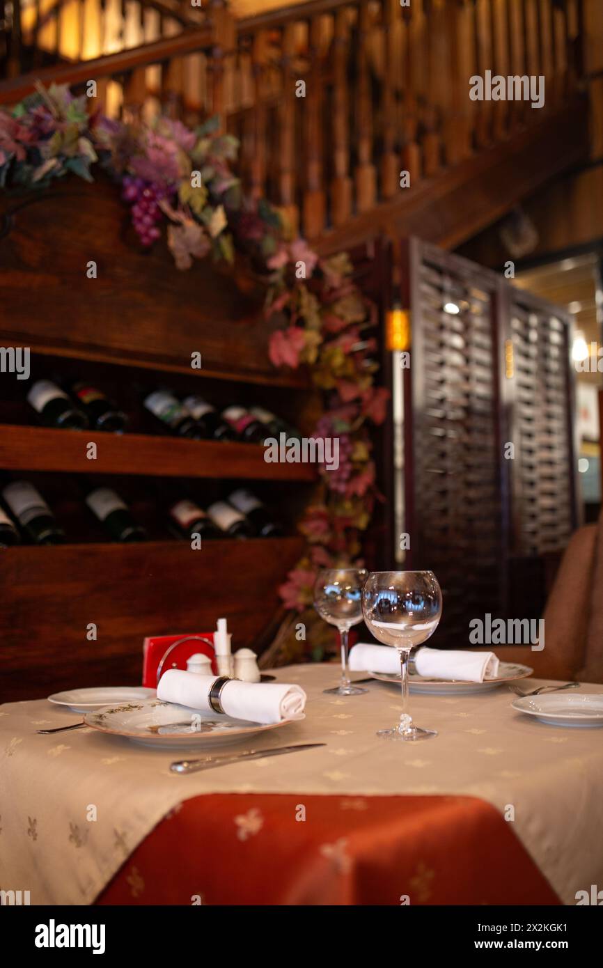 The image shows an elegant restaurant table setting with wine glasses ...