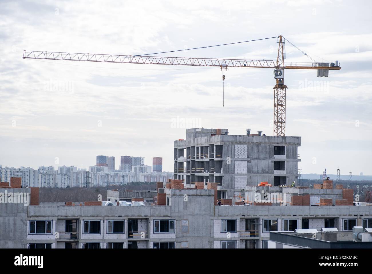 A crane and a building under construction against a blue sky background ...