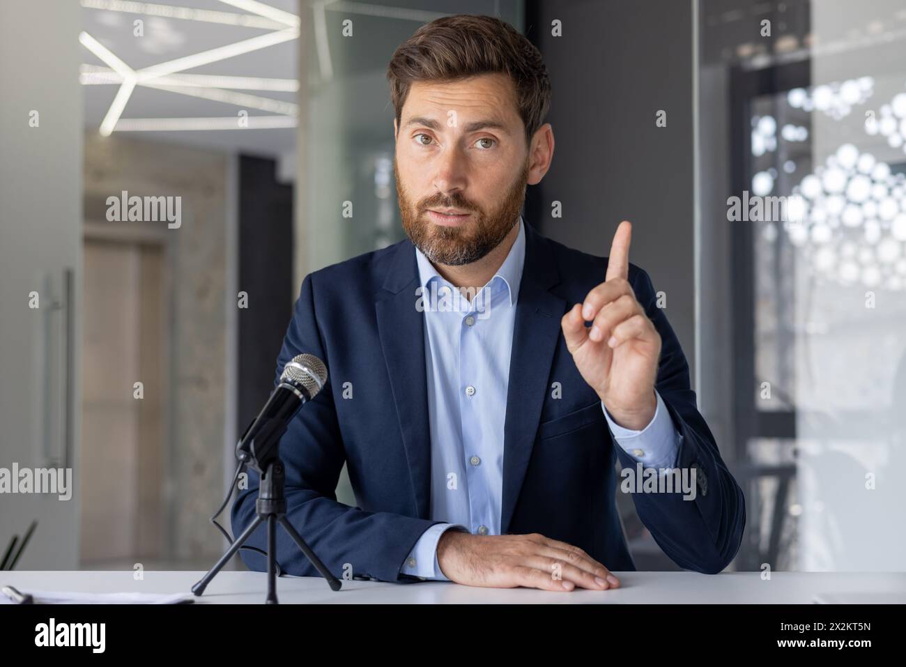Confident professional man speaking and raising his finger as if making ...