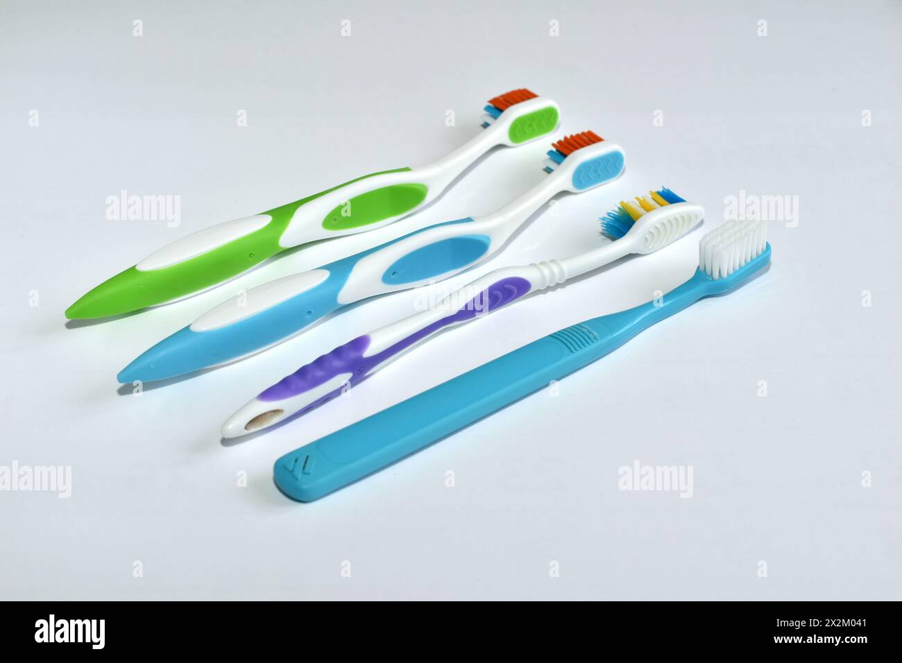 On a white background, toothbrushes of different colors lie in one row ...