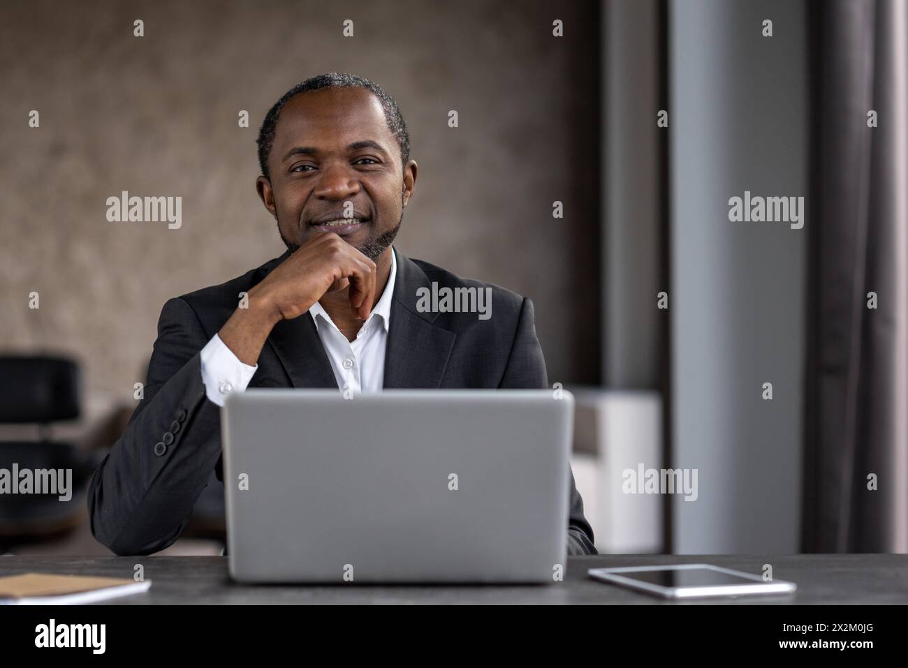 A professional black businessman smiles confidently in a modern office ...