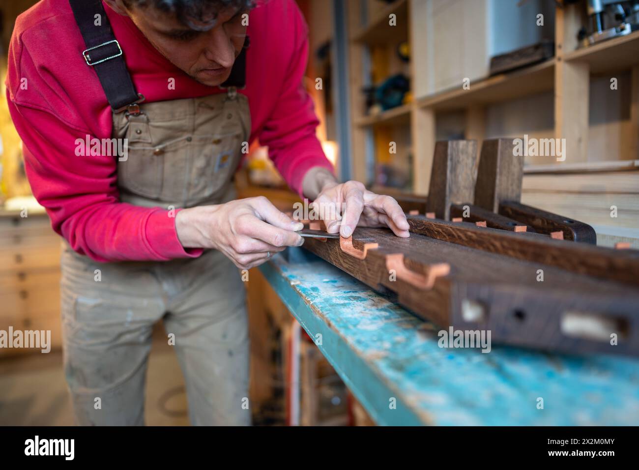 Focused carpenter man works with handmade slatted base of bed. Careful ...