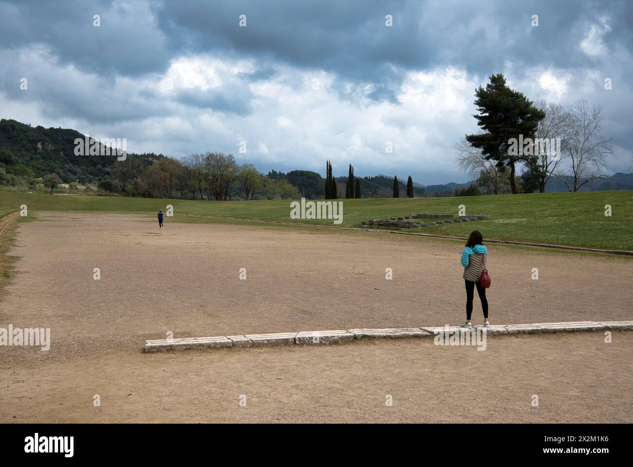 Tourist running in the Ancient Stadium of Olympia on a stormy Spring ...