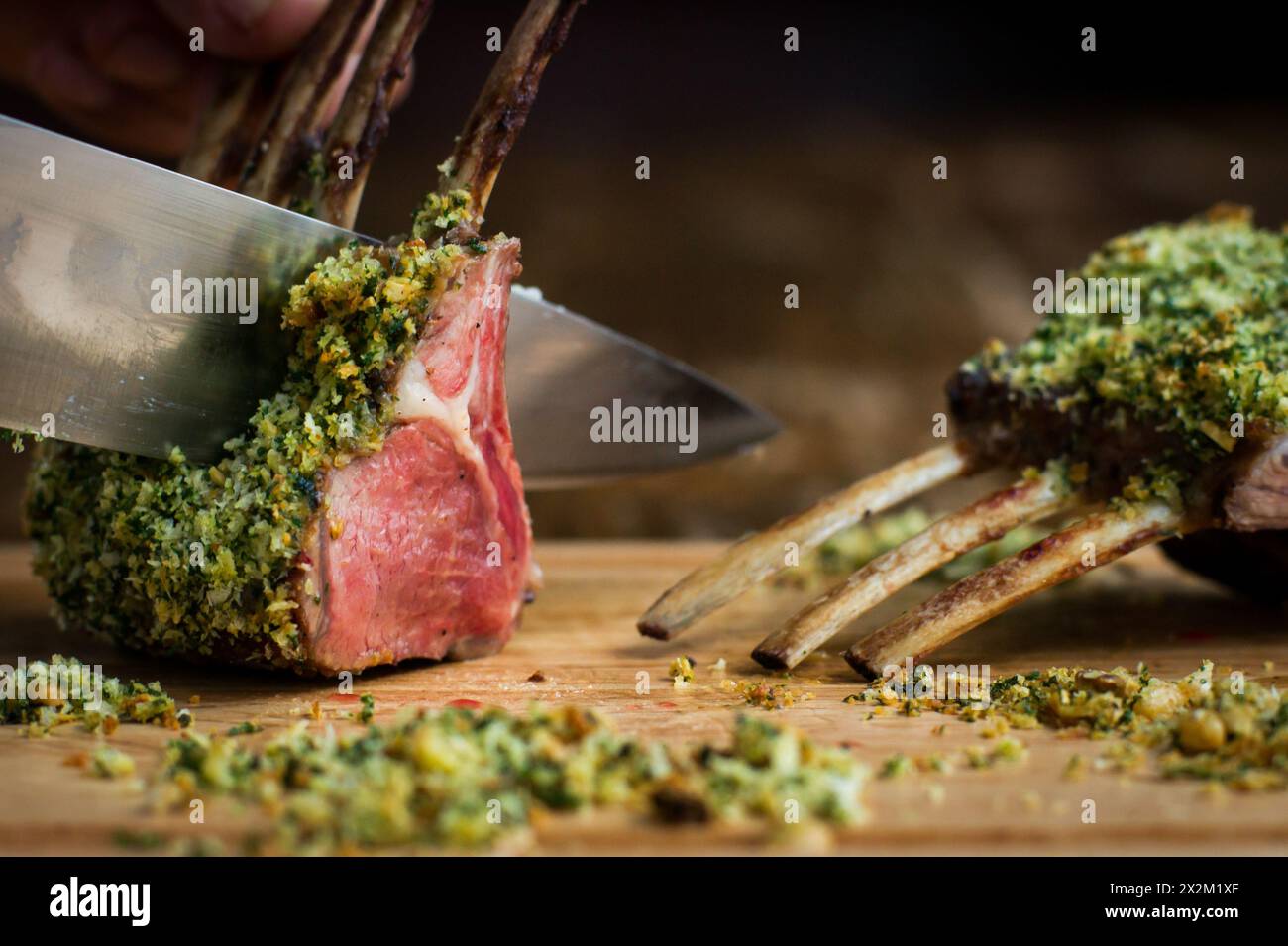 Rack of lamb with hazelnut herb crust being cut with large knife on ...