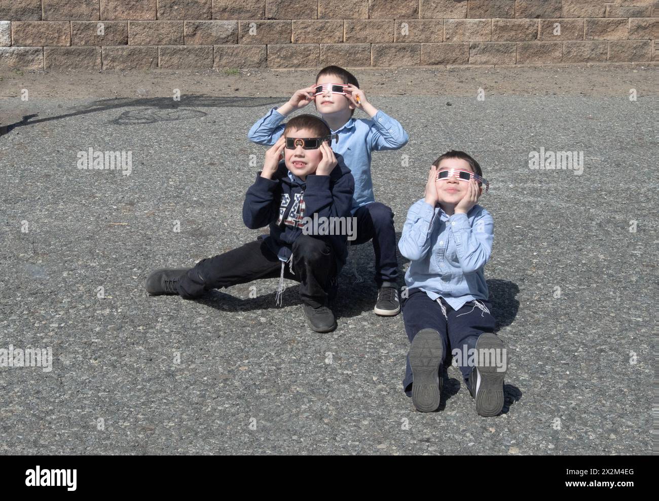 3 orthodox Jewish children watch the 2024 eclipse in the schoolyard of ...