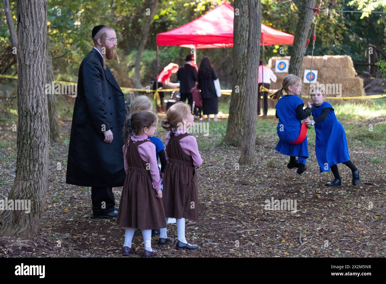 An orthodox Jewish family celebrates a holiday on swings at a farm in ...