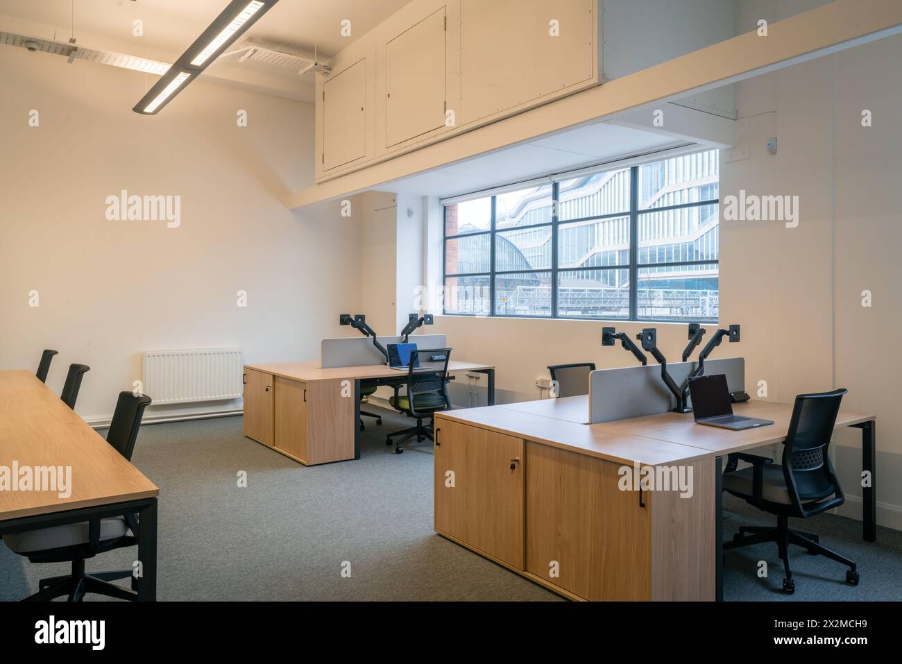 A contemporary office space with wooden desks, chairs, computers, and a ...