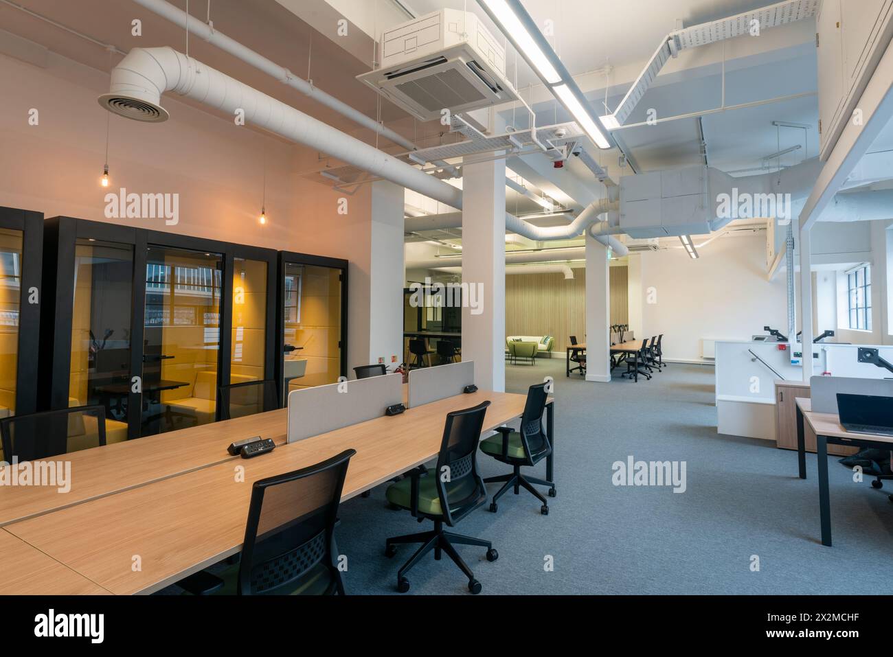 A contemporary open workspace featuring rows of desks, ergonomic chairs ...