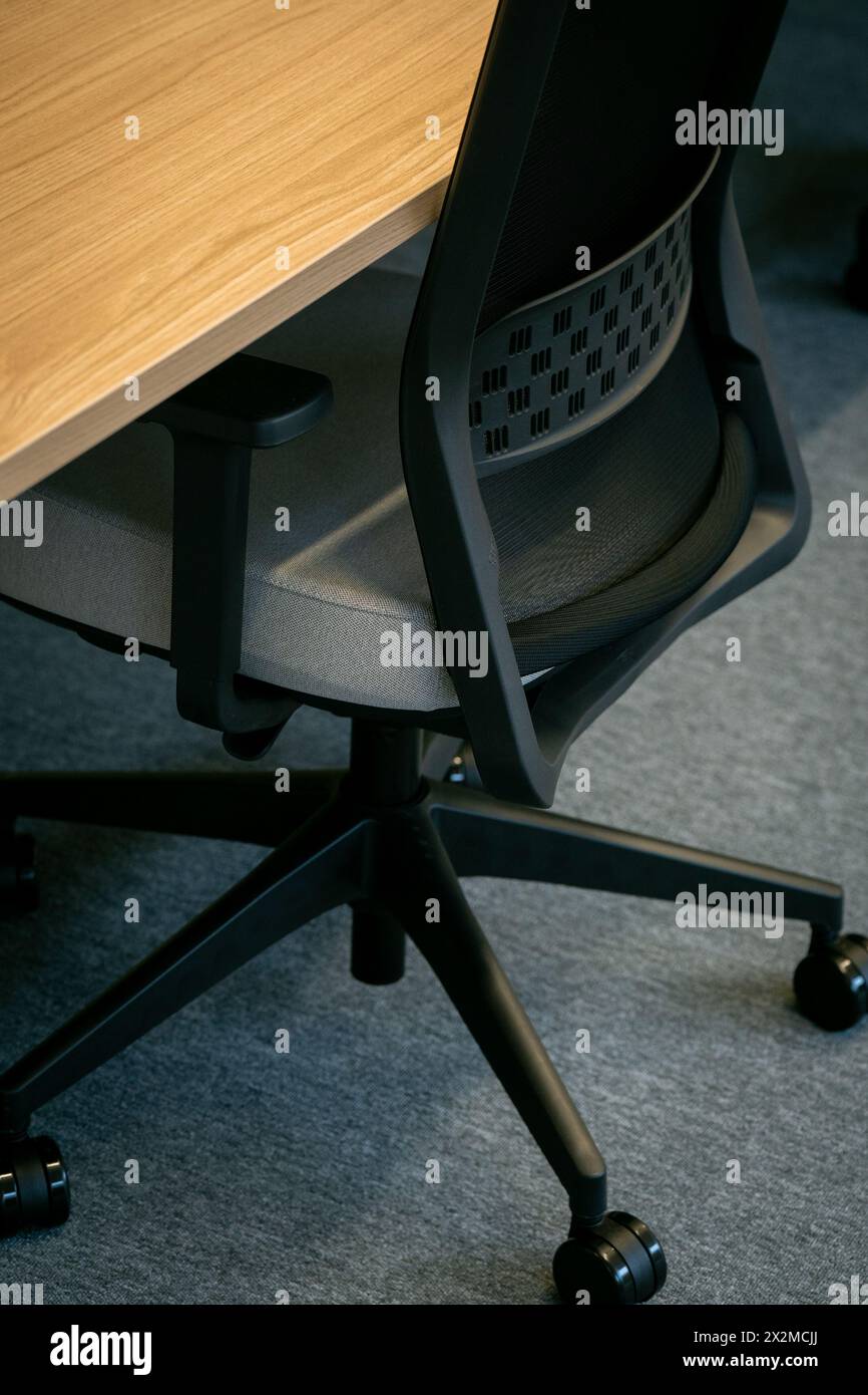 A close-up view of a contemporary office chair and wooden desk ...