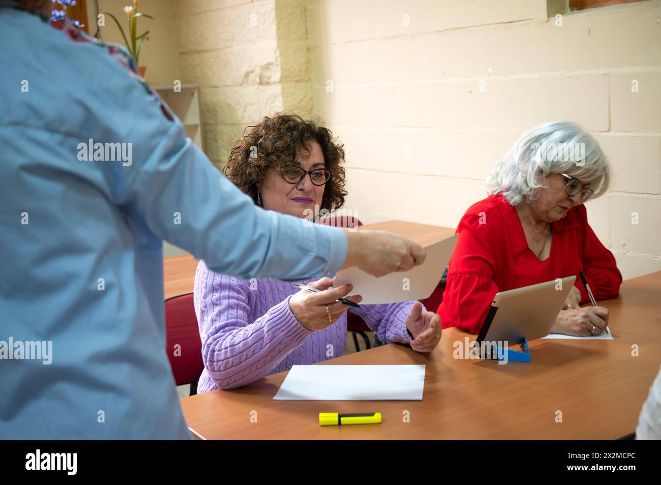 Senior adults engage in a learning activity in a classroom environment ...