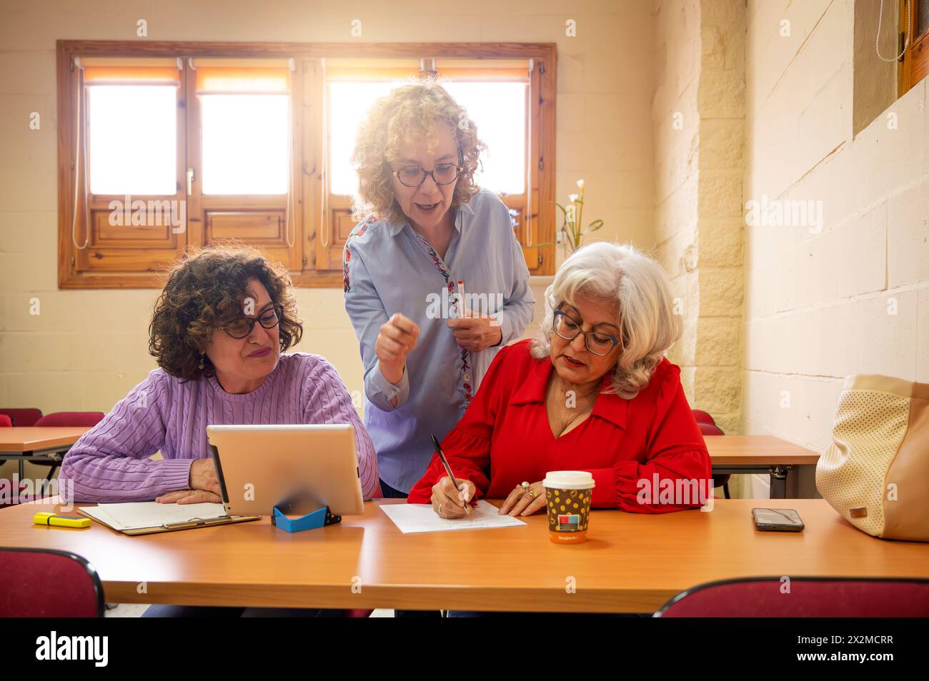 Three senior women actively participate in an educational setting, with ...