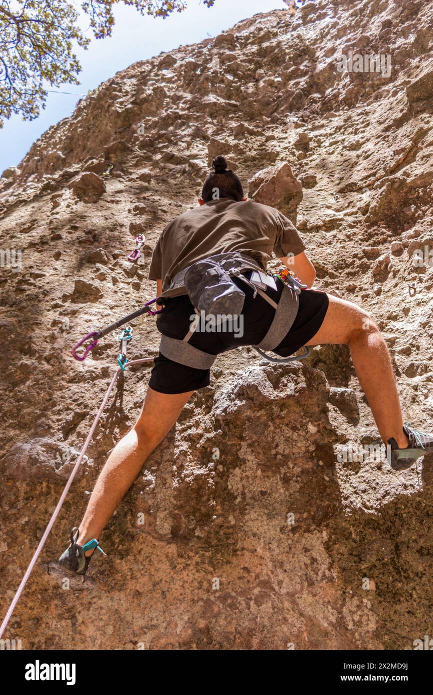 An adventurer engages in rock climbing, ascending a steep, rugged cliff with determination ...