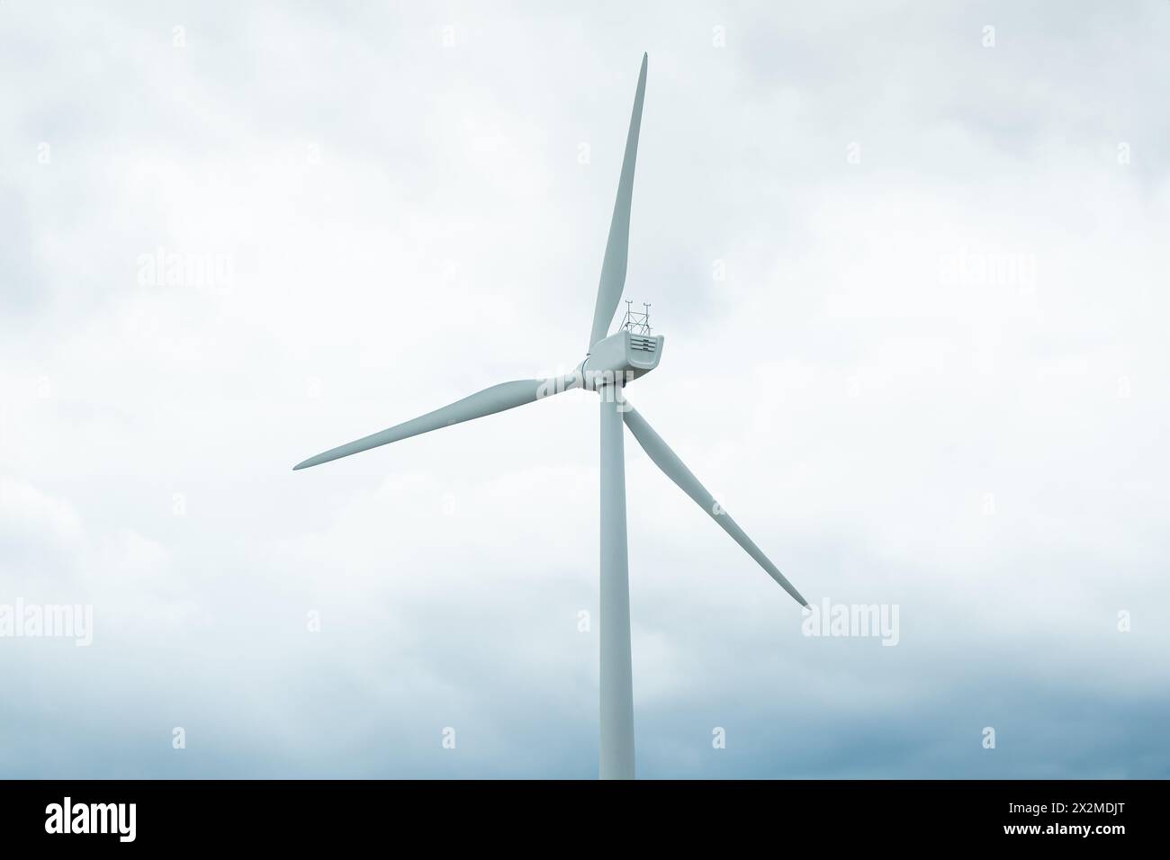 A single wind turbine standing tall with a backdrop of a cloudy sky ...