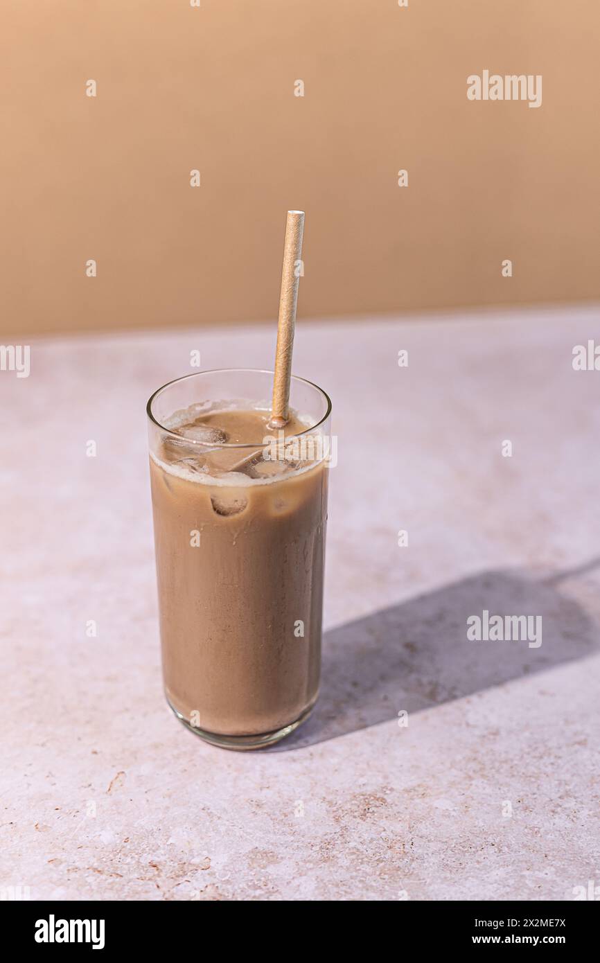 A tall glass of creamy iced coffee, complete with ice cubes and an eco ...