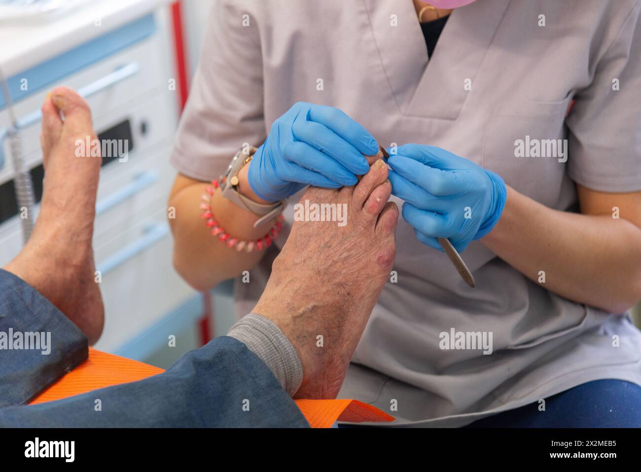 An elderly man is having his toenails treated by a podiatrist wearing ...