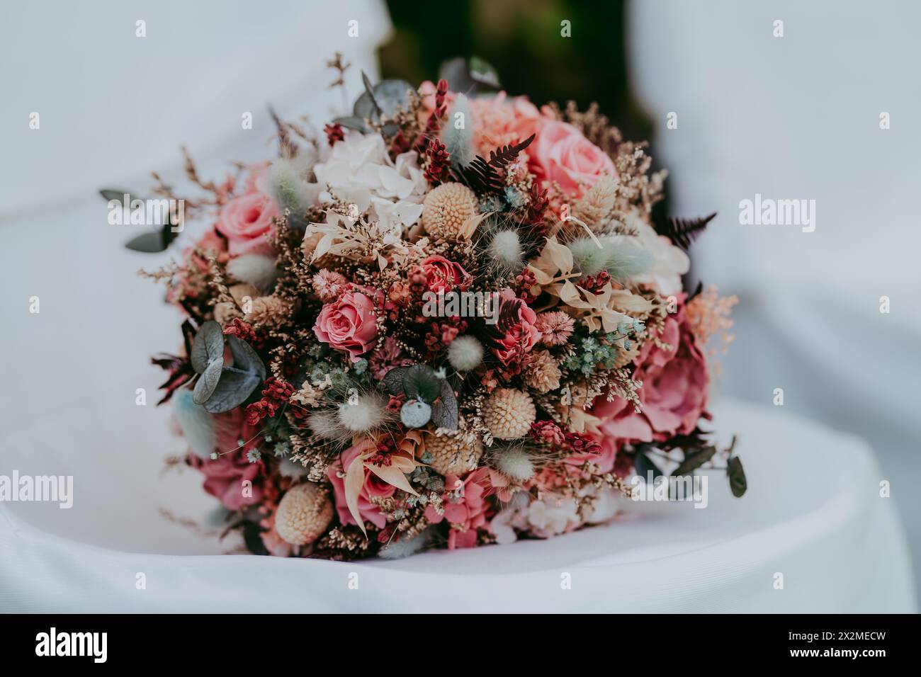 A detailed bridal bouquet displays a mix of roses, daisies, and various ...