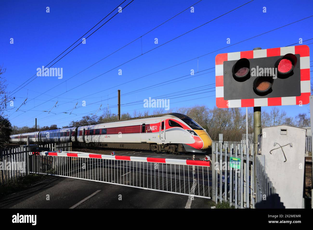 An Azuma train passing red lights at an Lolham unmanned Level crossing, East Coast Main Line ...