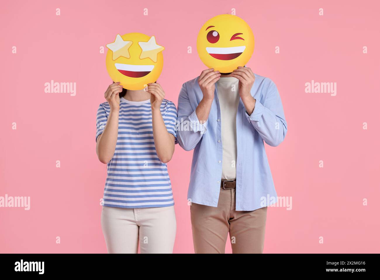 People covering faces with emoticons on pink background Stock Photo - Alamy