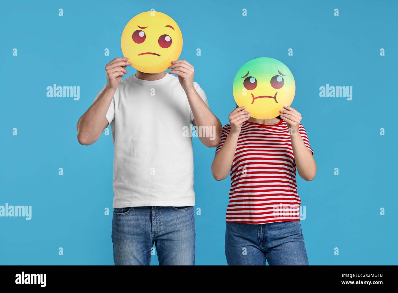 People covering faces with emoticons on light blue background Stock ...