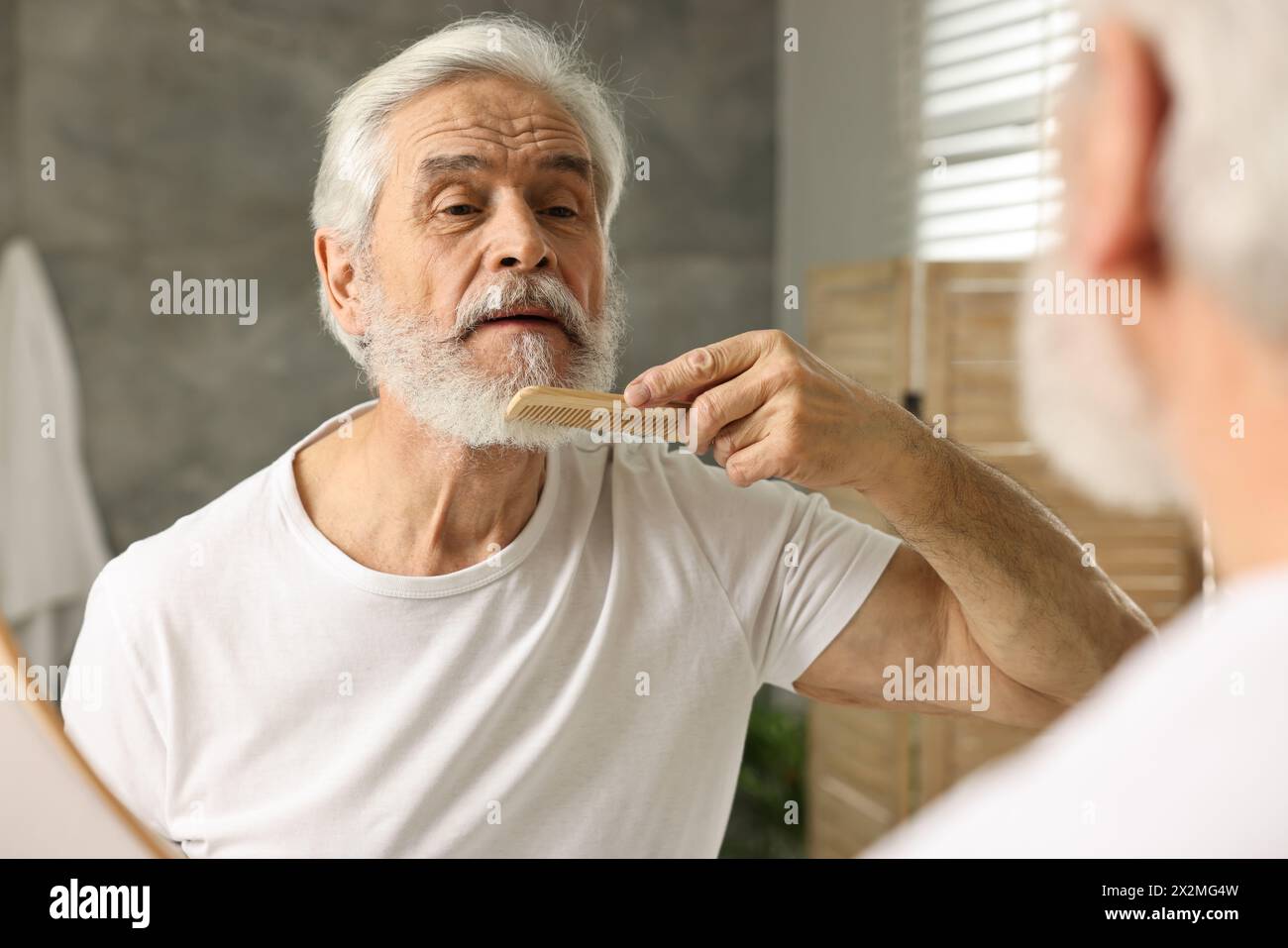 Senior man with mustache combing beard near mirror in bathroom Stock ...