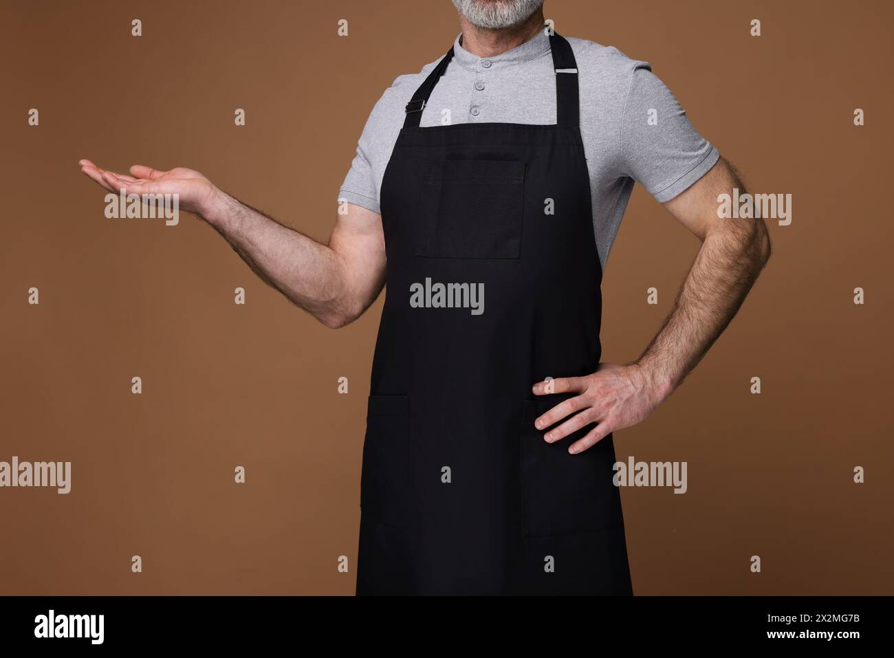 Man wearing kitchen apron on brown background, closeup. Mockup for ...