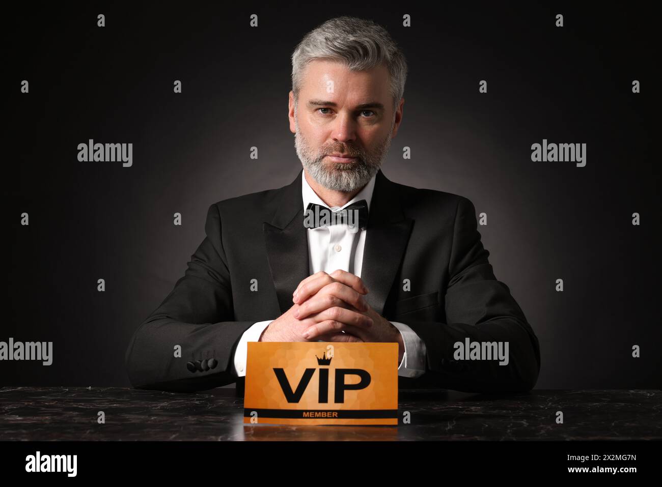 Handsome man sitting at table with VIP sign on black background Stock ...