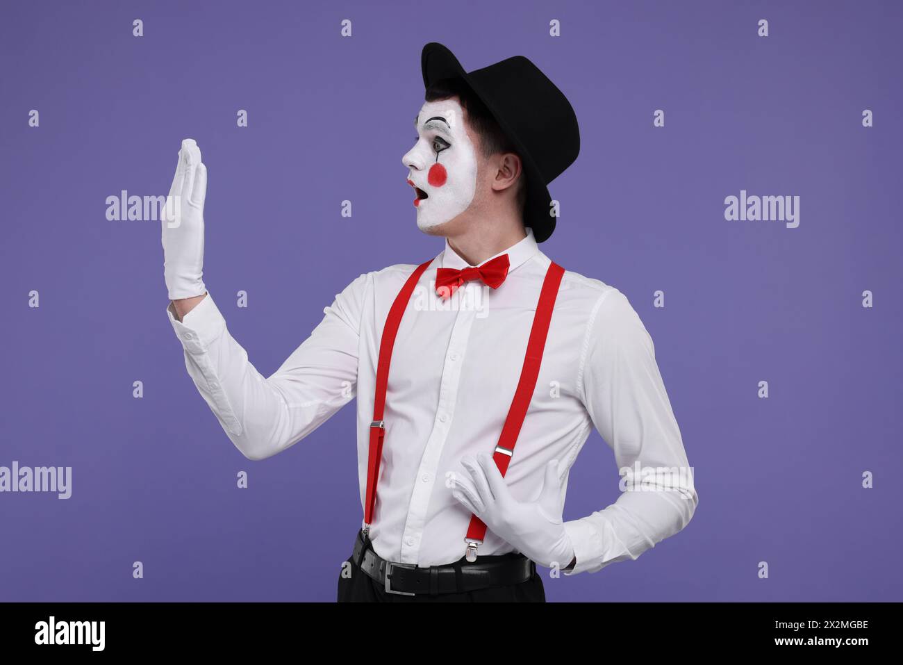 Mime artist making excited face on purple background Stock Photo - Alamy