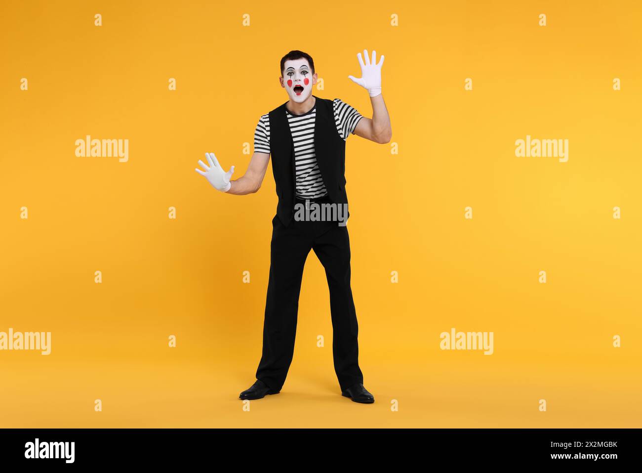 Mime artist making shocked face on orange background Stock Photo - Alamy