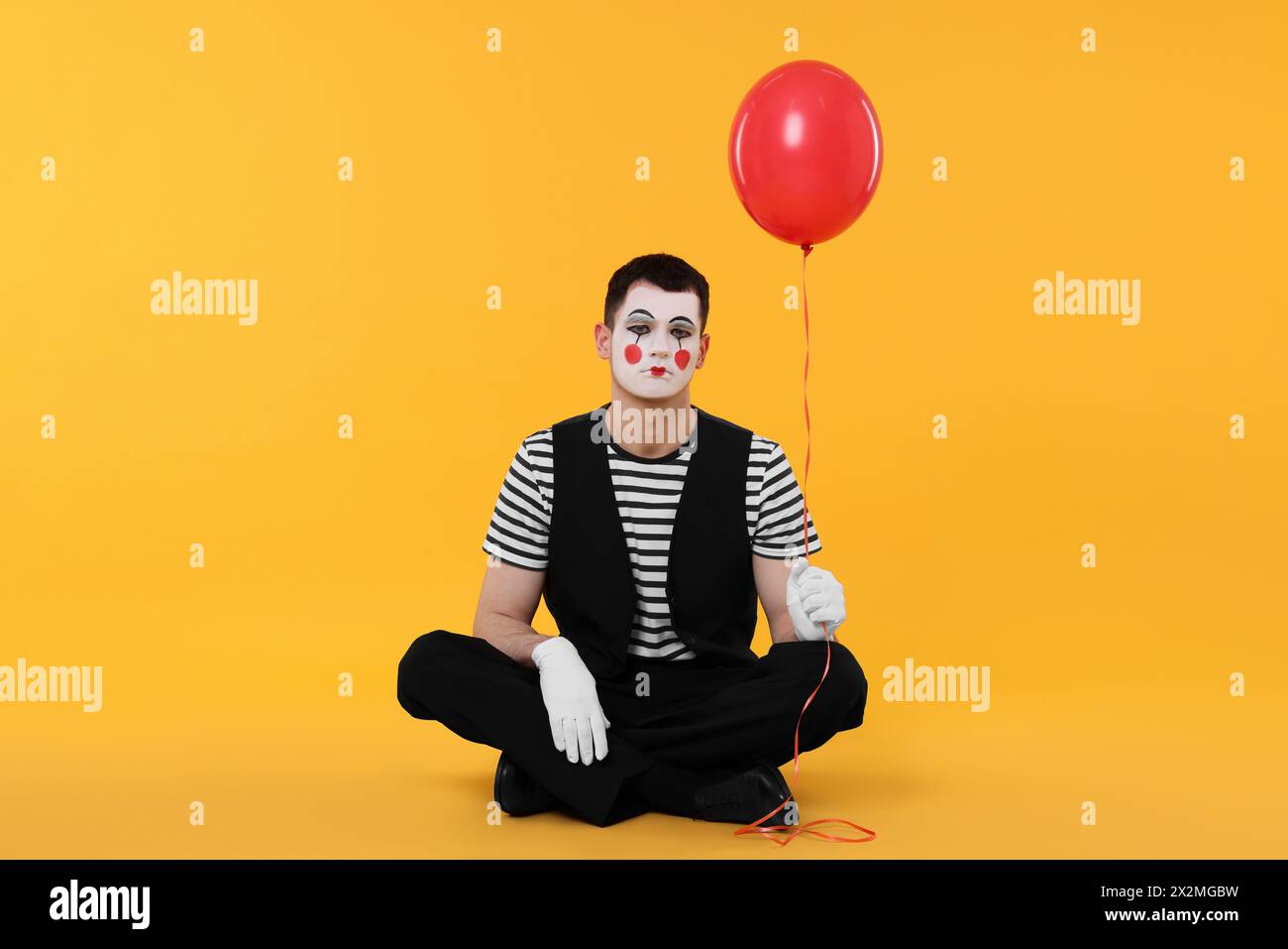 Funny mime artist with balloon on orange background Stock Photo - Alamy
