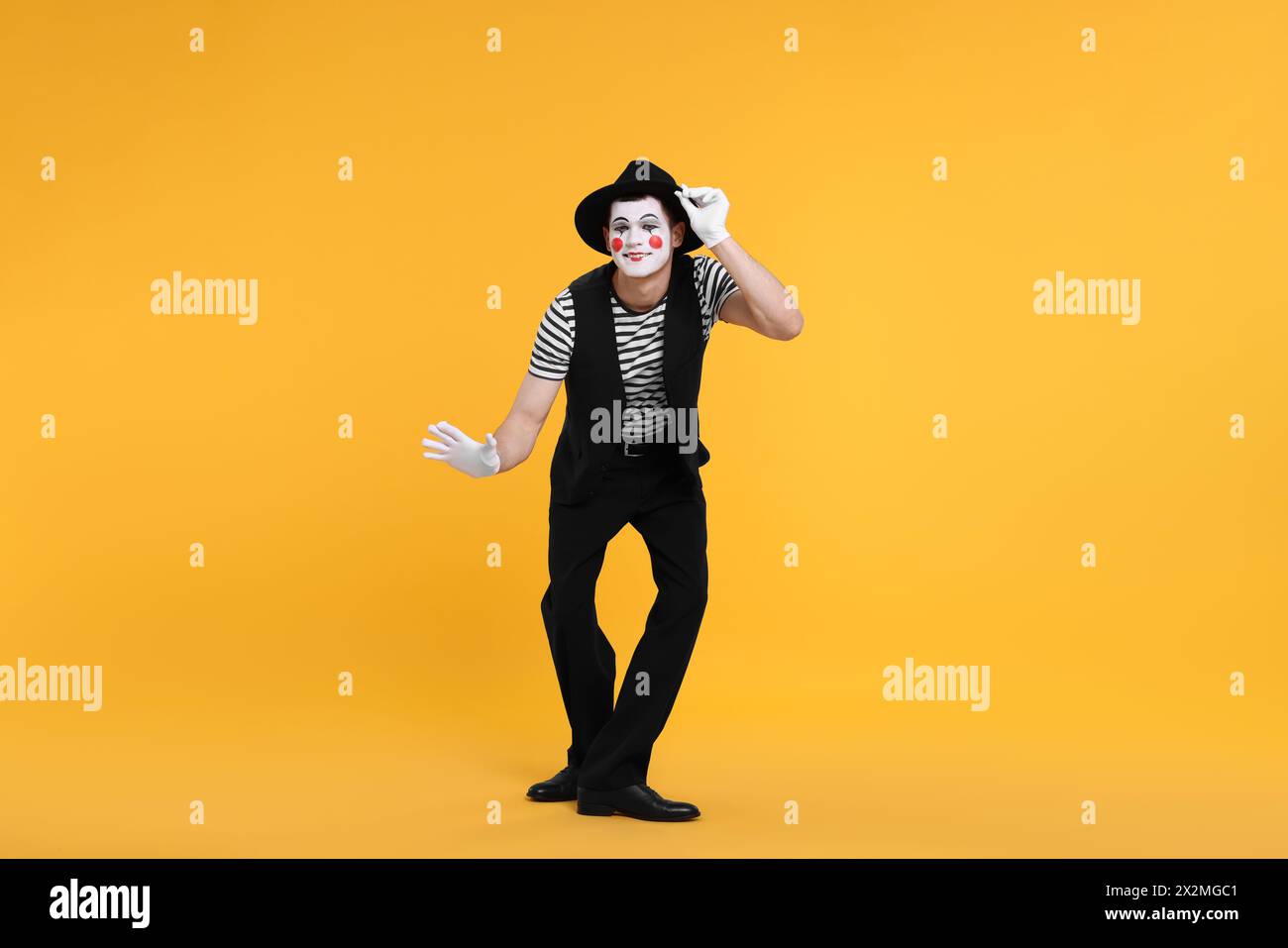 Funny mime artist in hat posing on orange background Stock Photo - Alamy