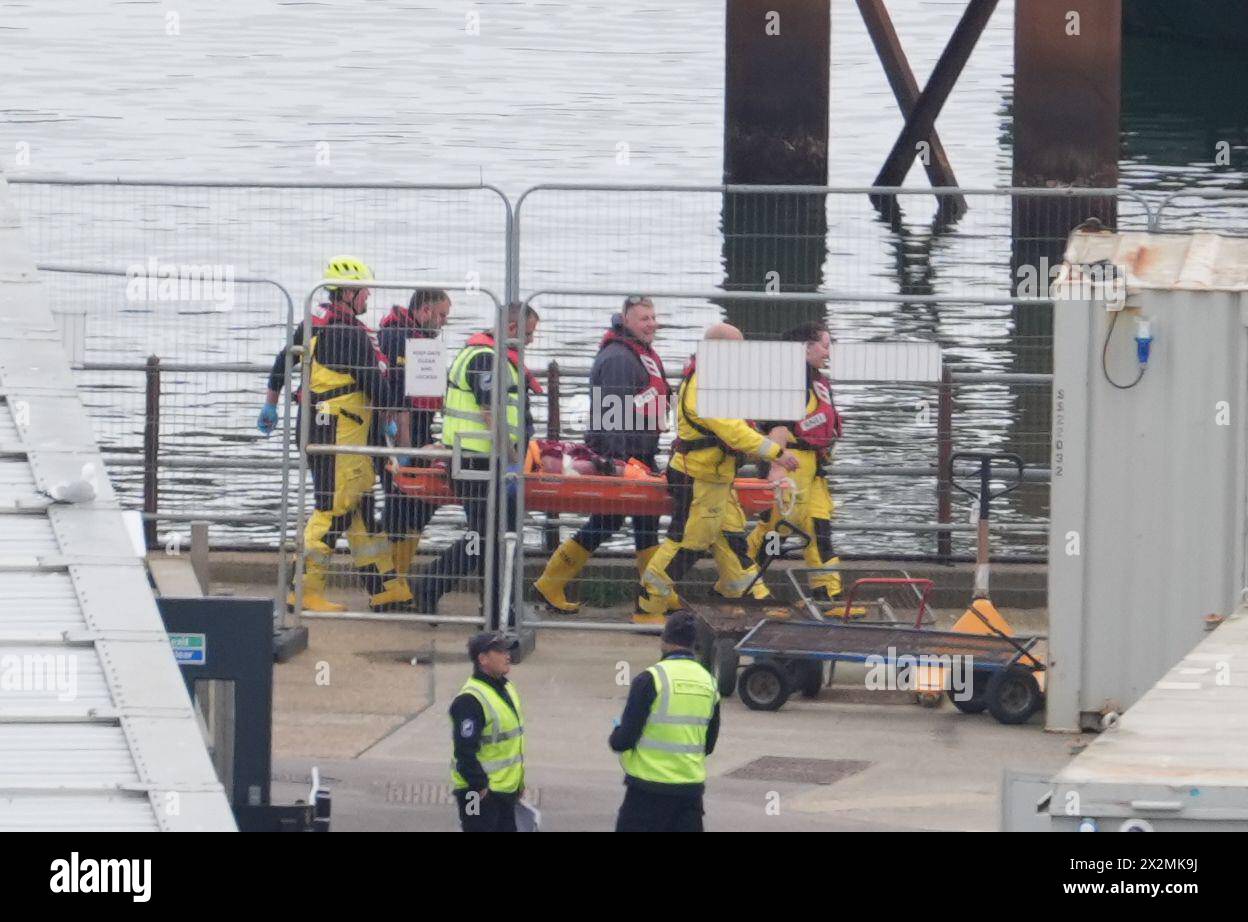 An RNLI crew carry a person in a stretcher towards an ambulance in to ...