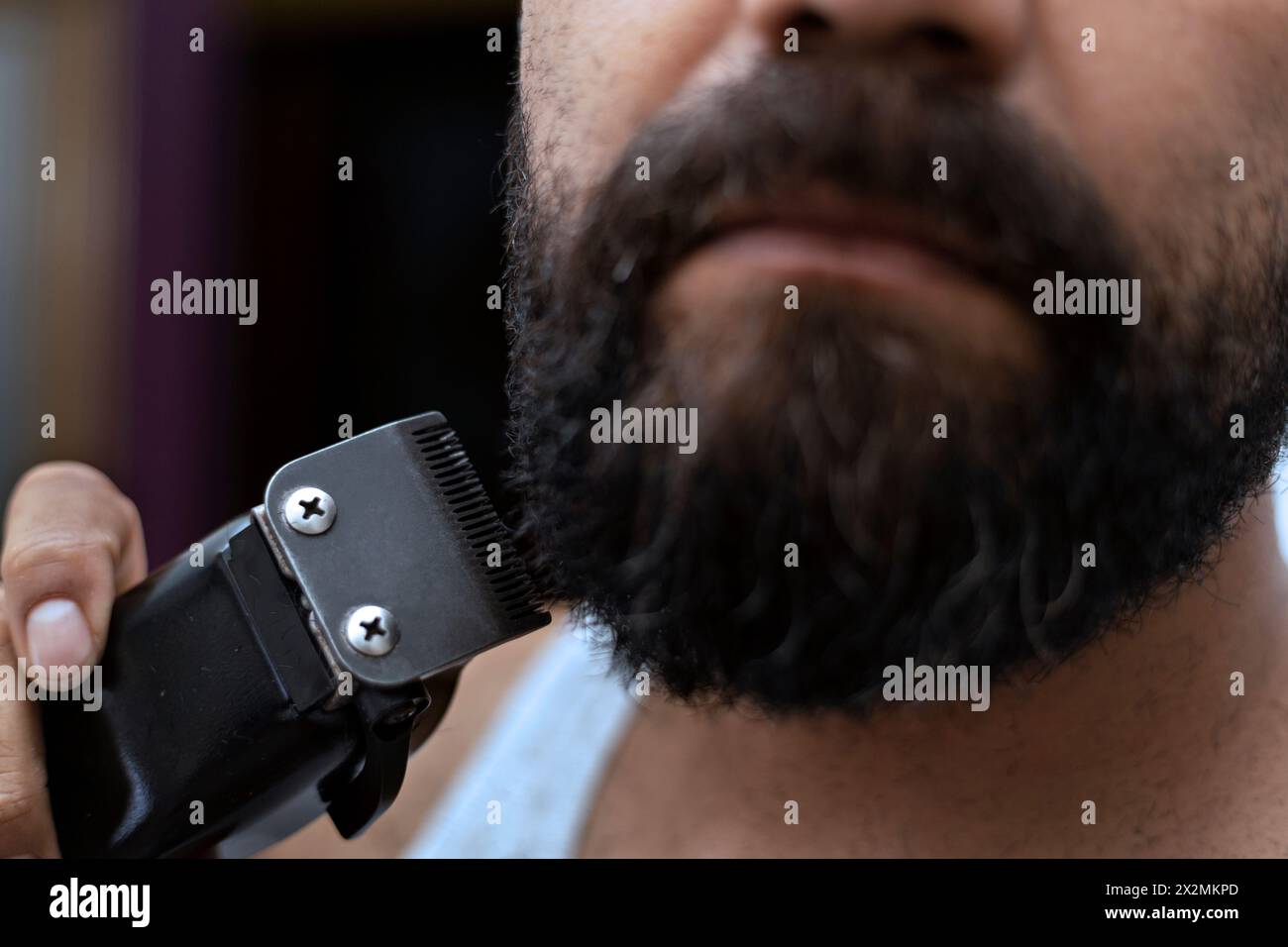 Latin man (39) cuts his own beard with a razor in front of a mirror ...