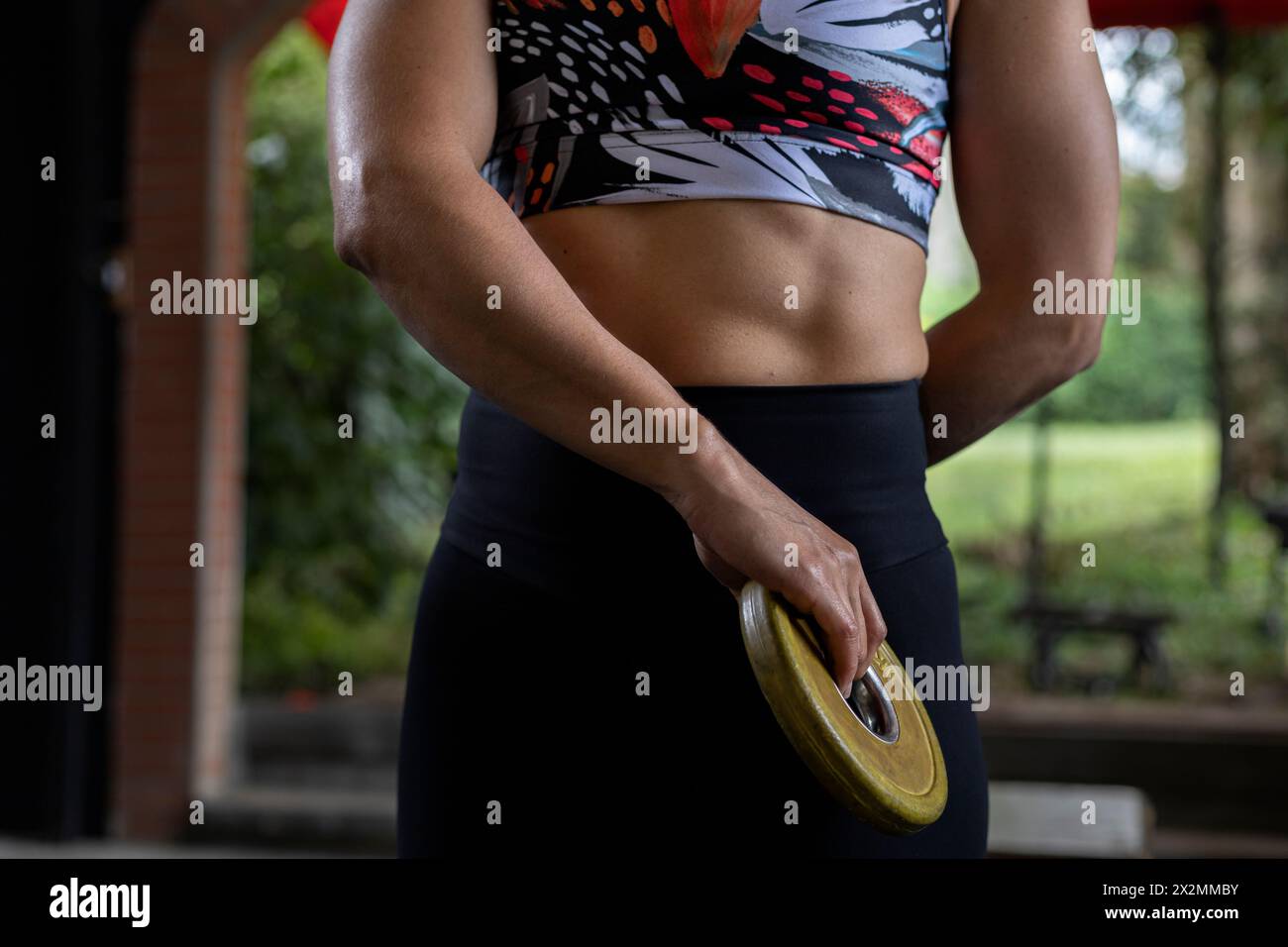 Latin American woman holds a dumbbell in her hand as she performs arm ...