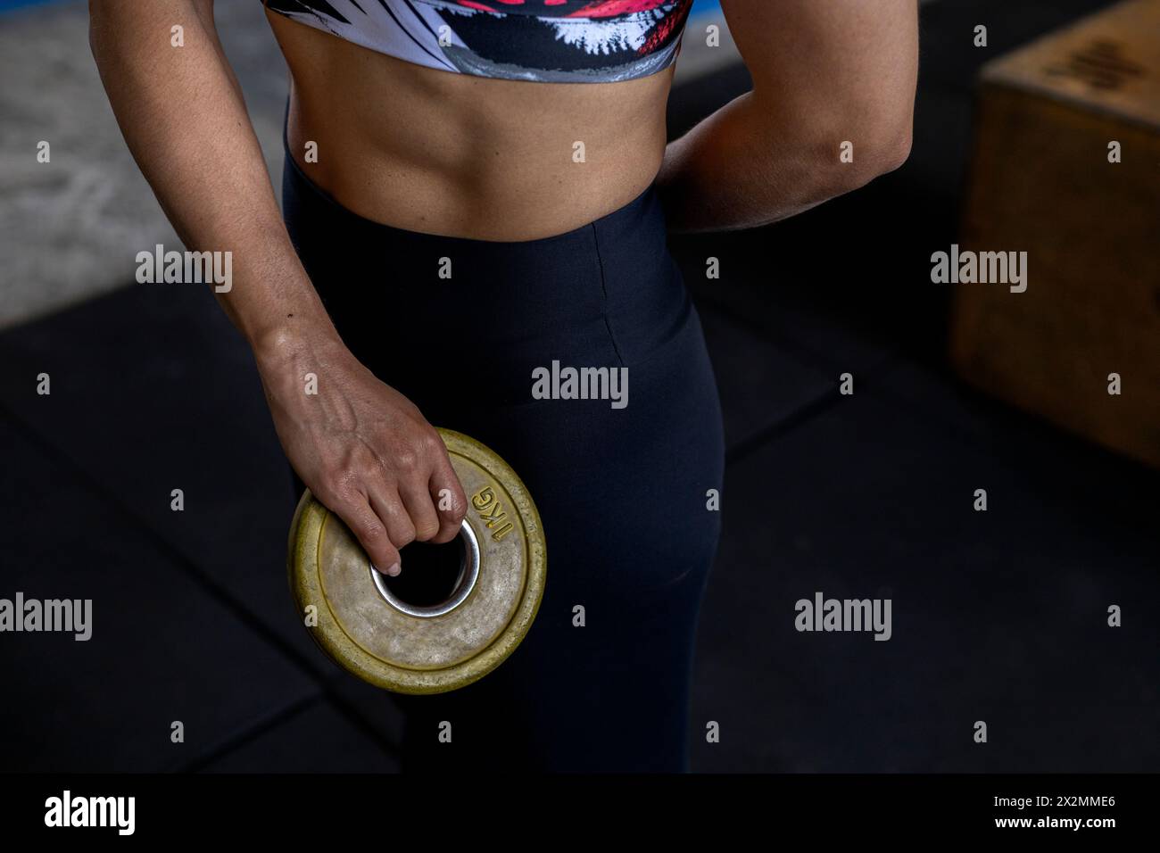 Latin American woman holds a dumbbell in her hand as she performs arm ...