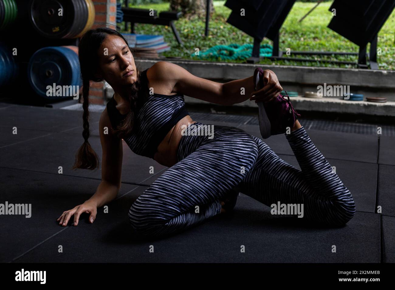 Young Latin American woman performing stretching and bending exercises ...