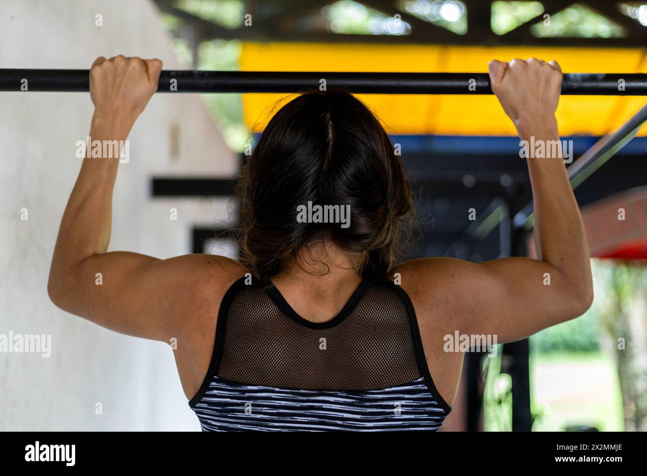 Young Latin American woman tests her arm strength on the calisthenics ...