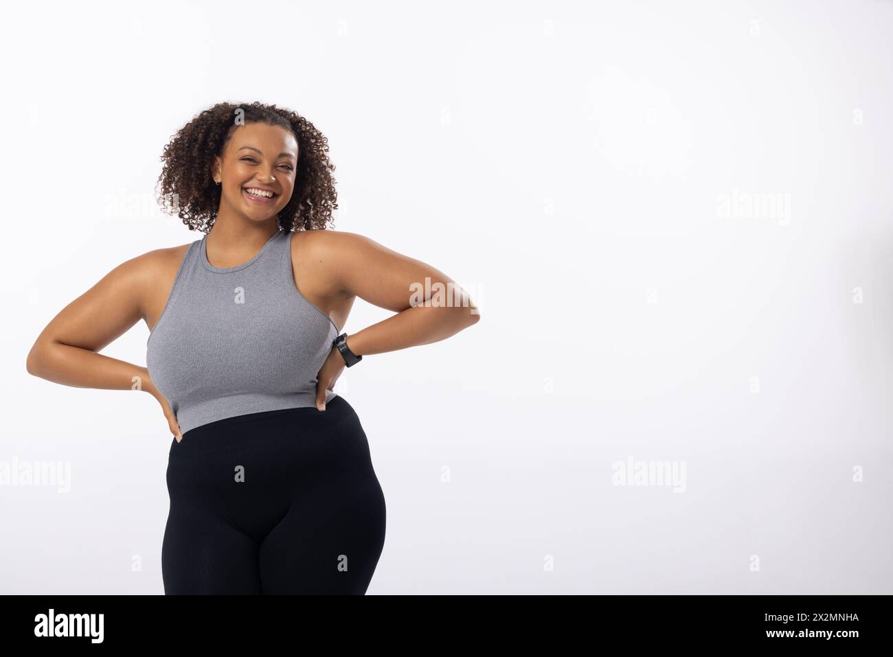 Biracial plus size female model with hands on hips, white background ...