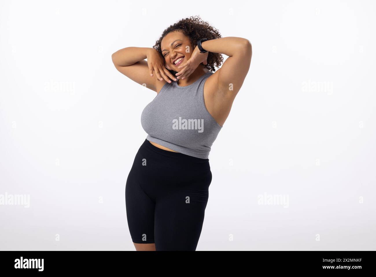 Biracial plus size young female model poses, hands on head, smiling ...