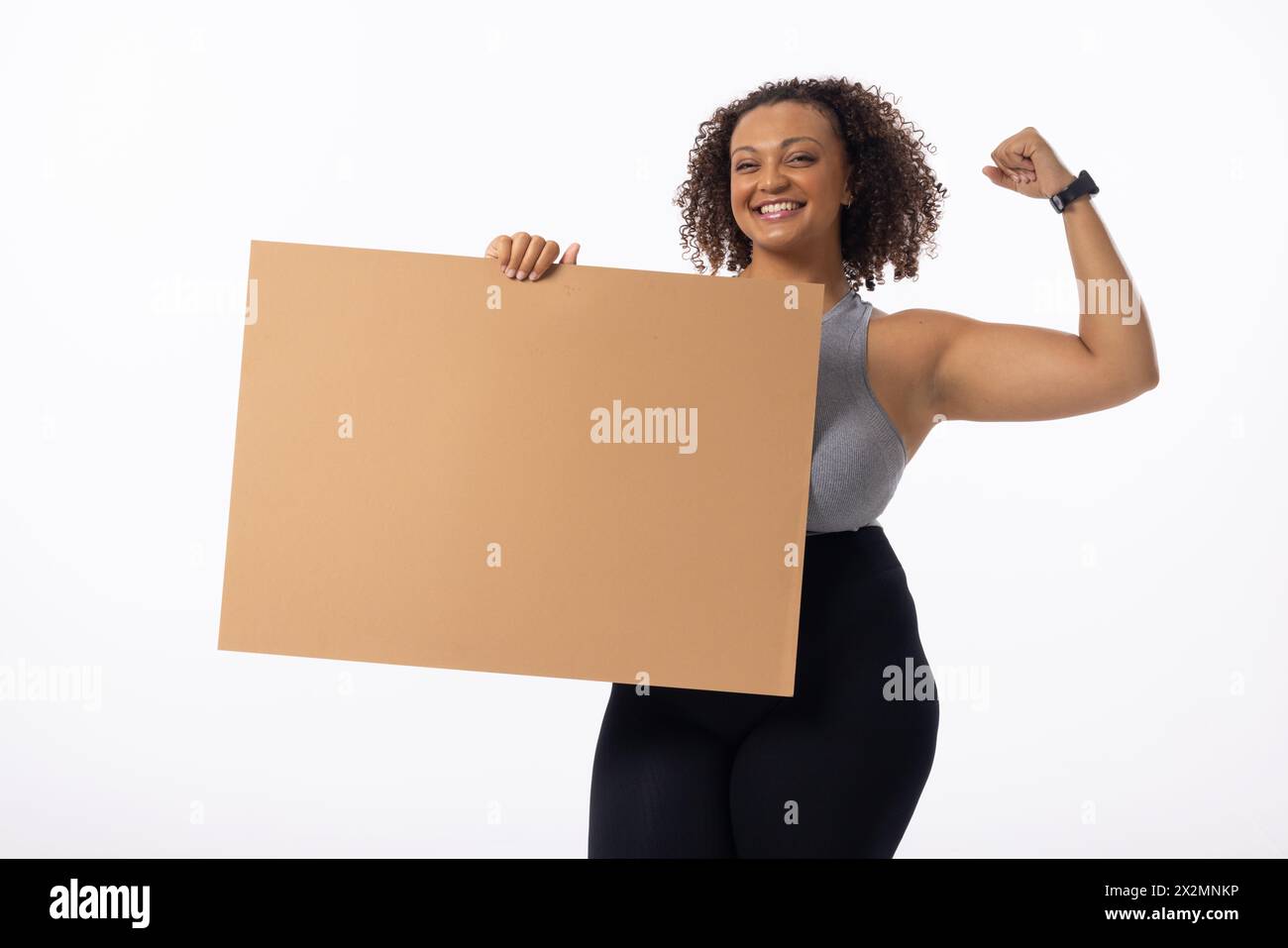 A biracial young female plus size model flexes her arm on white ...