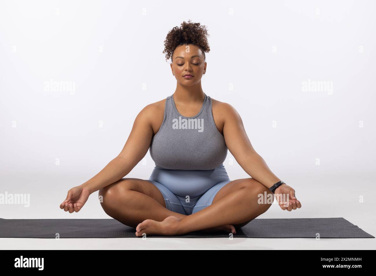 Biracial young female plus size model practices yoga on white ...