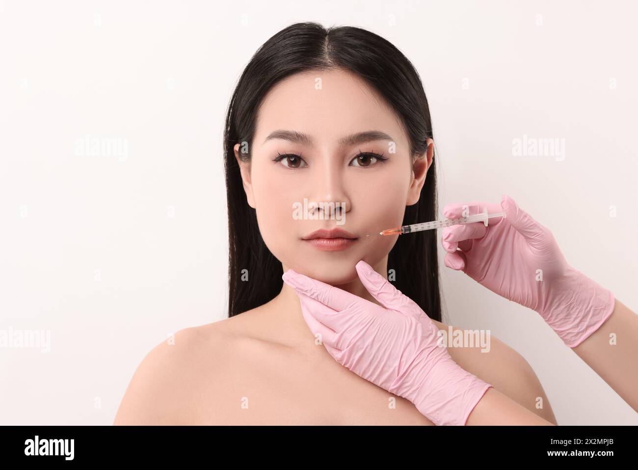Woman getting lip injection on white background Stock Photo - Alamy
