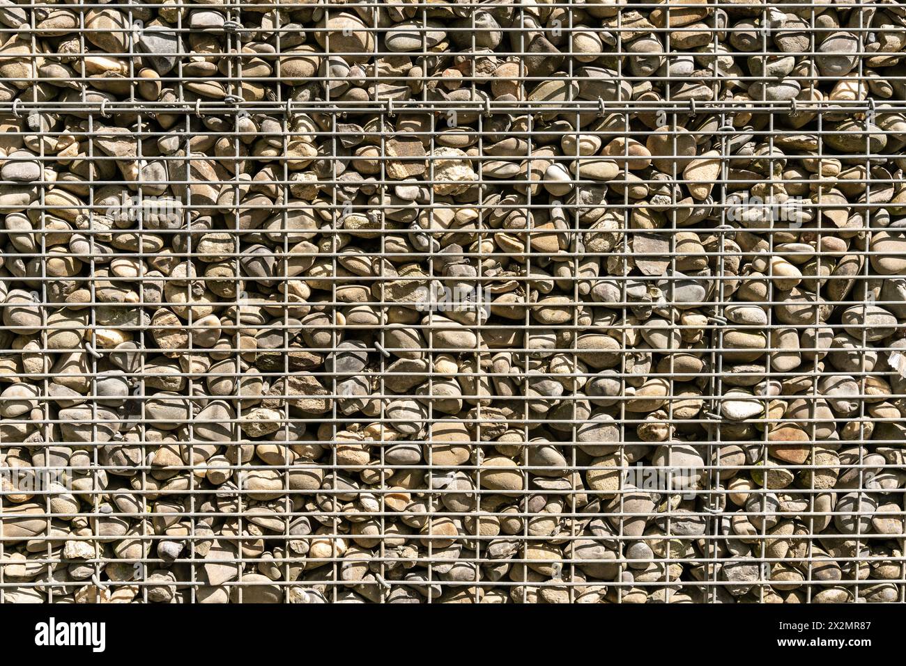 Texture of pebbles in metal grille cages stacked upon each other, used ...