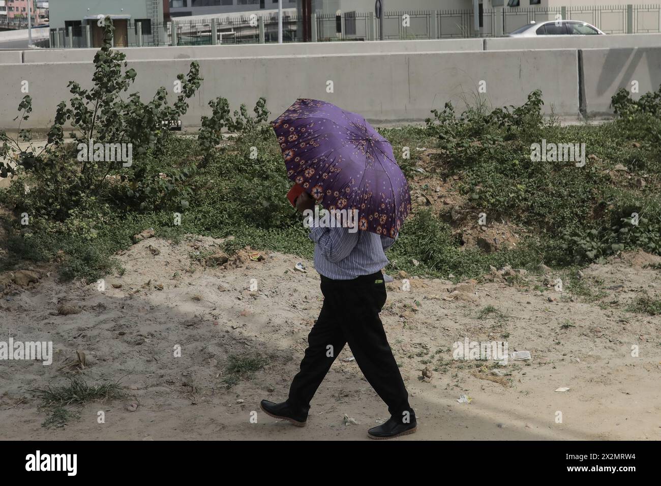 April 23, 2024: A pedestrian is using an umbrella to protect himself ...