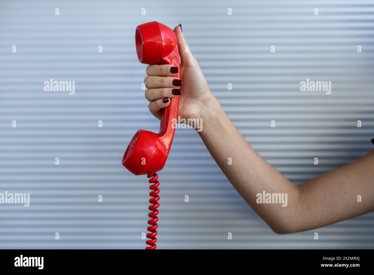 Red handset held by a woman's hand. Gray background. Vintage technology ...